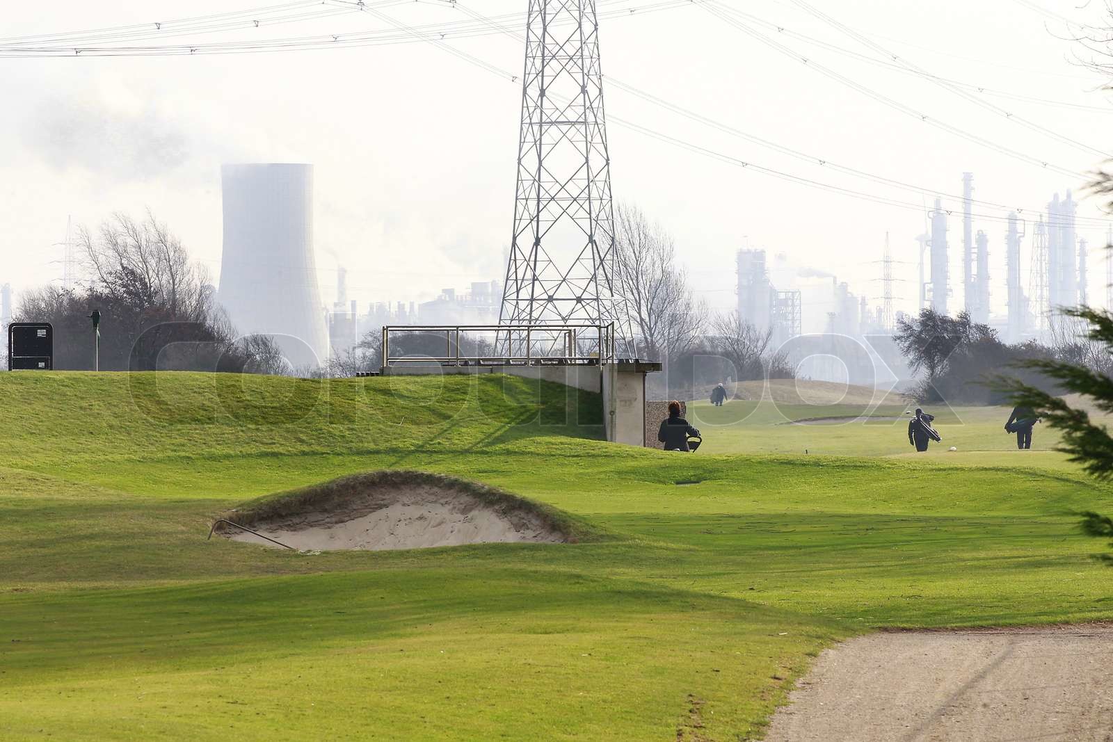 golf course with high-voltage mast above and nuclear power plant in the ...