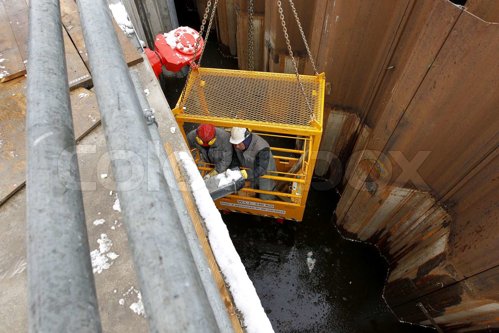 construction workers hanging in a cage working at a sluice | Stock ...