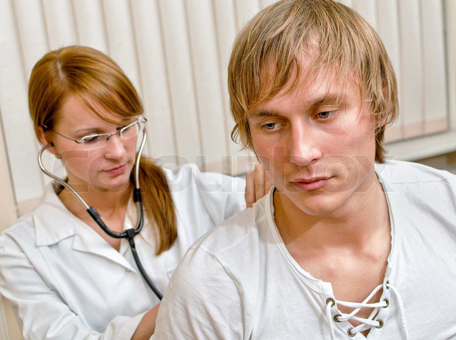 Young female doctor examine male patient with stethoscope Focus on ...