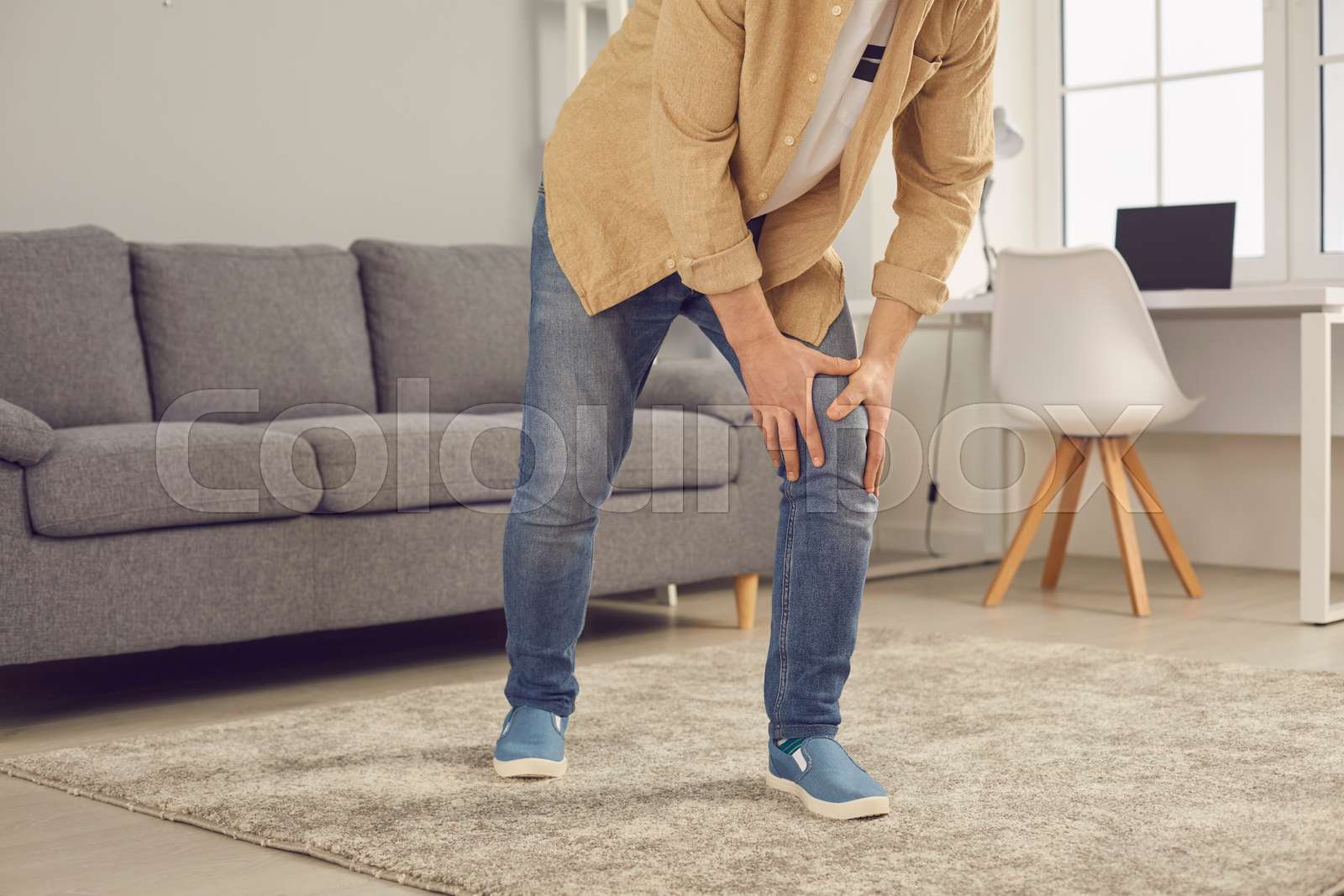Young man touching knee and suffering from pain at home | Stock image ...