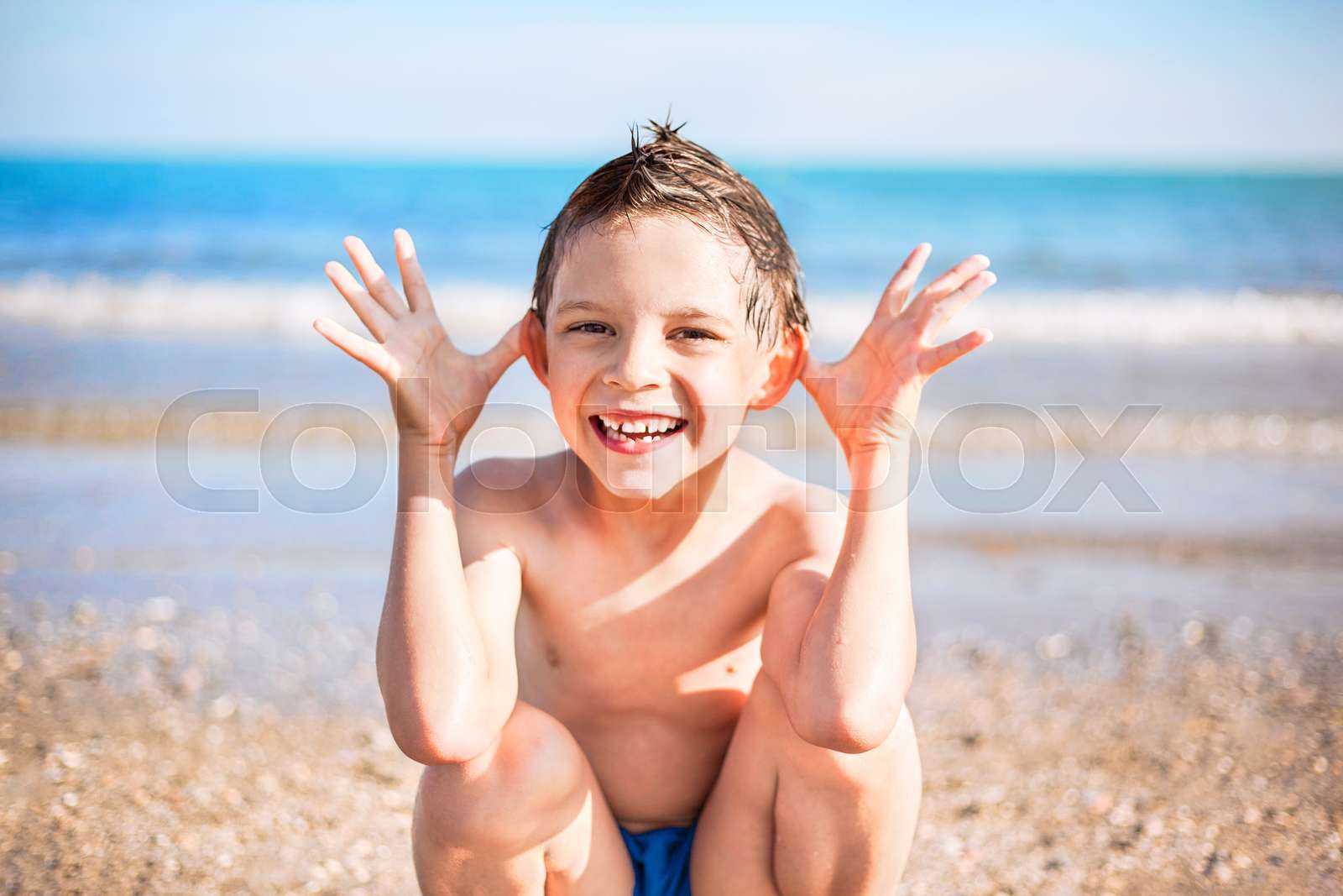 smiling boy sitting on the beach | Stock image | Colourbox