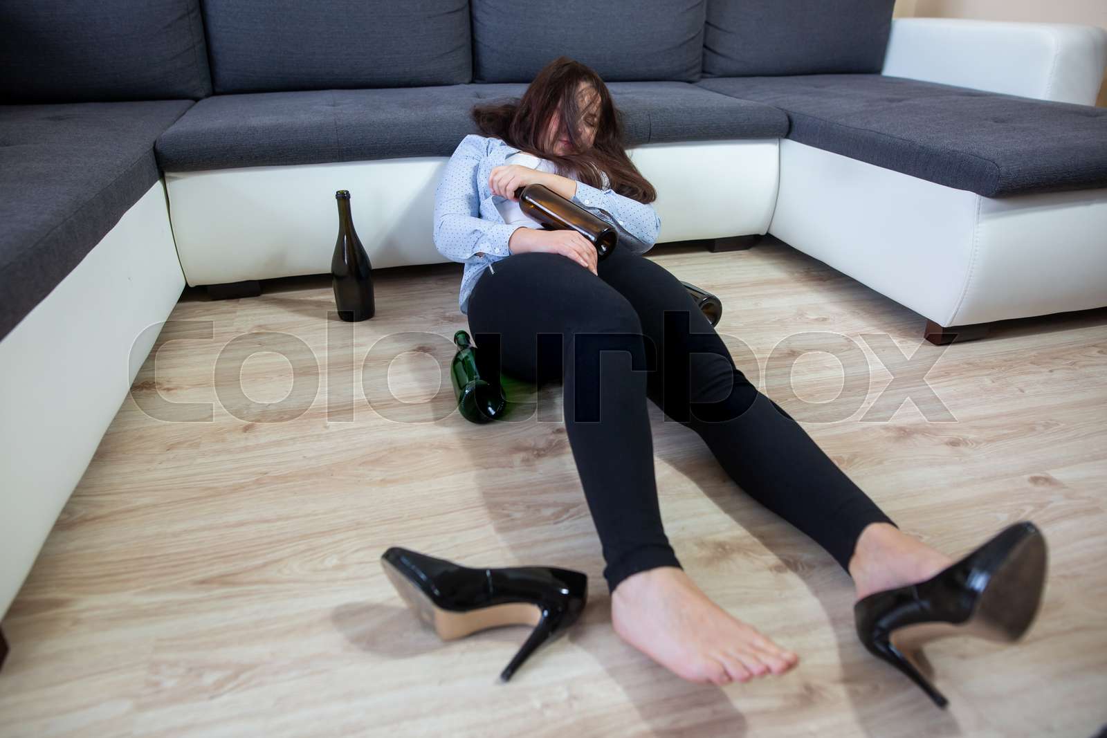 Drunk woman laying on the floor after huge party with some bottles of ...