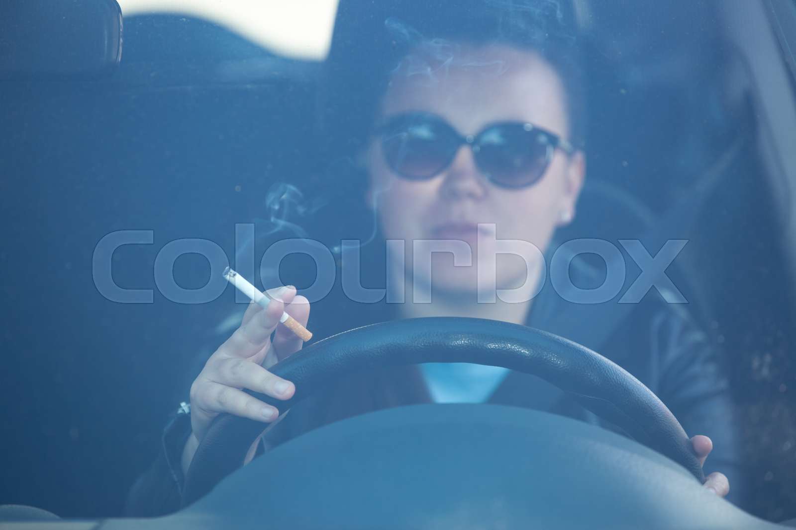 Close up of woman hand smoking cigarette inside the car while driving a ...