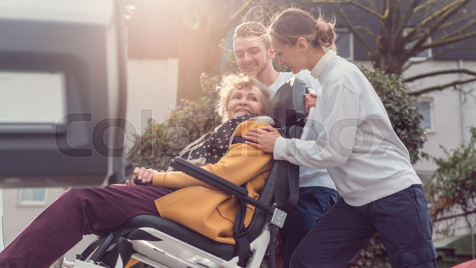 Two helpers picking up disabled senior woman for transport | Stock ...