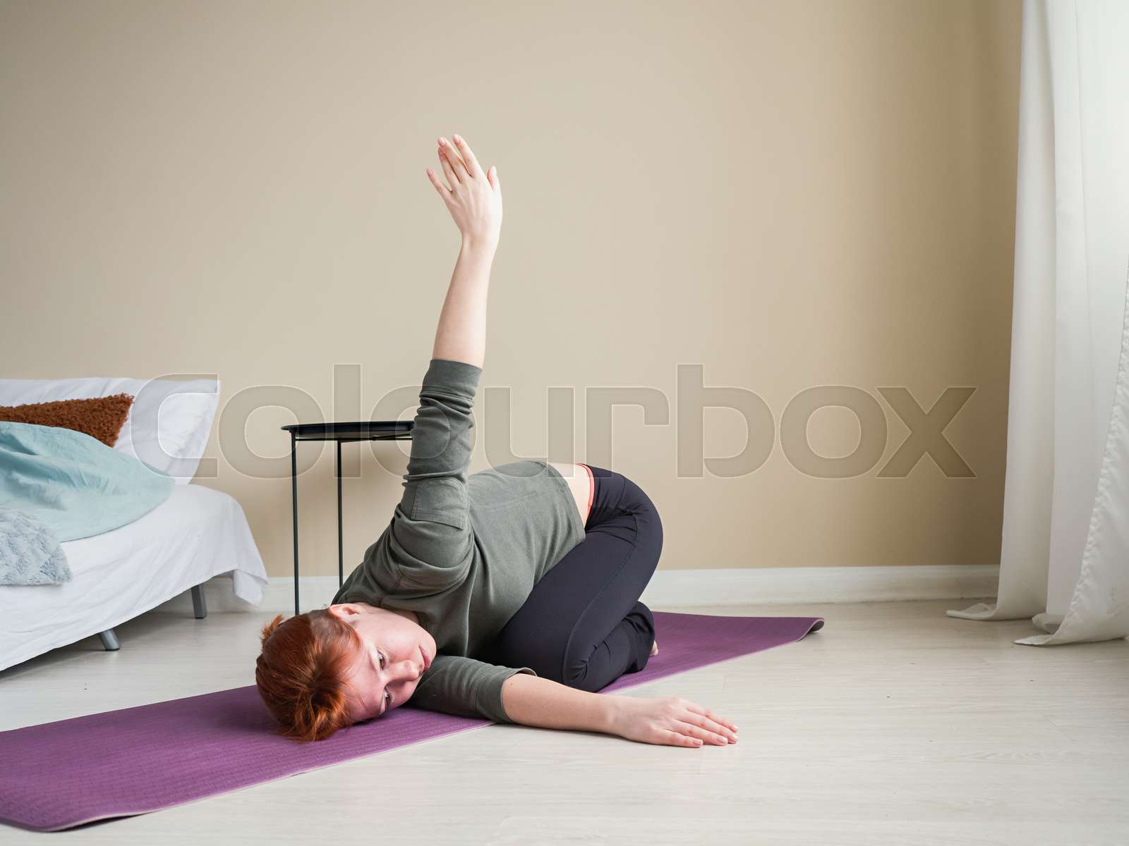 Woman stretching on yoga mat at bedroom. Stretching exercises at home ...