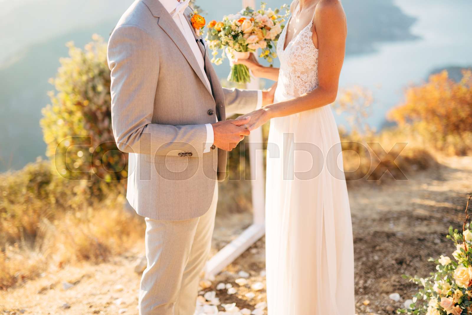 The bride and groom are standing on Mount Lovcen near the wedding arch ...