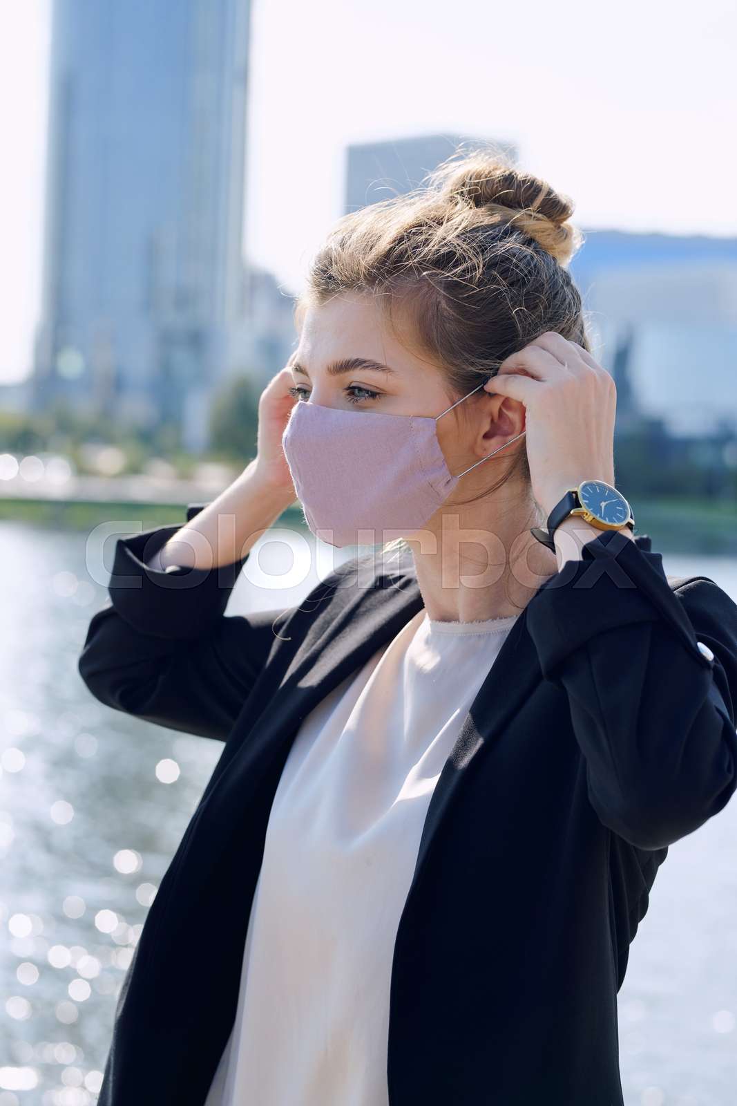 Young elegant blond businesswoman in formalwear putting on protective ...