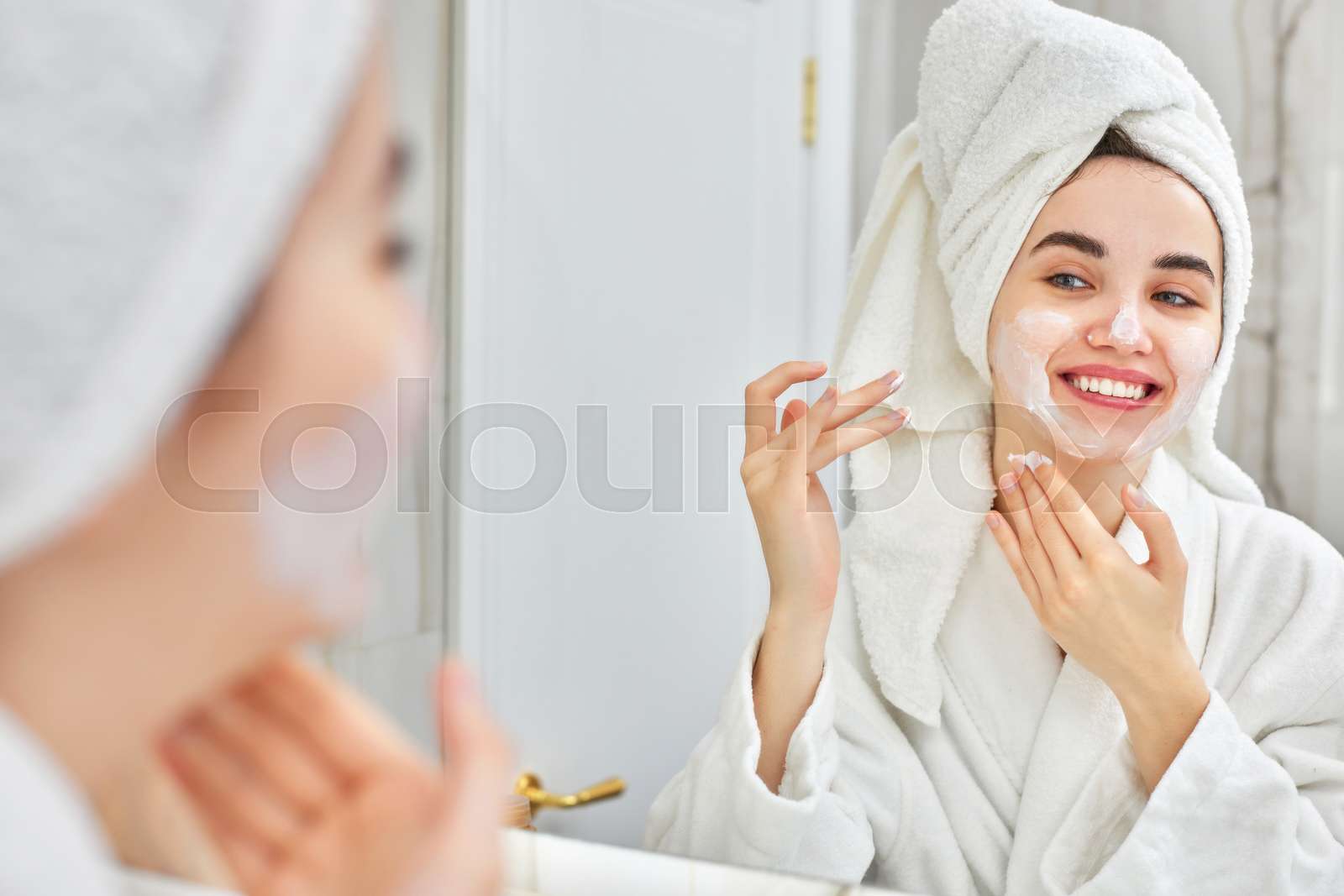 Woman In White Bathrobes Applying Apply Facial Cream Stock Image