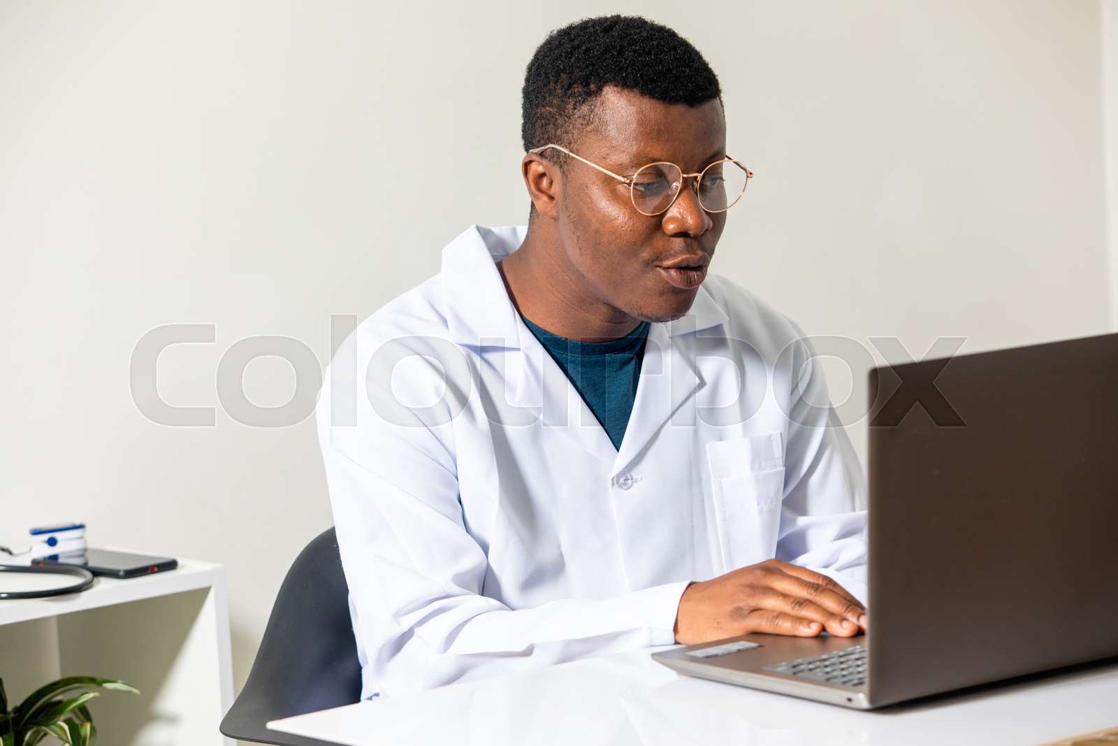 Young doctor gaining new knowledge using laptop - Stock Image - Everypixel