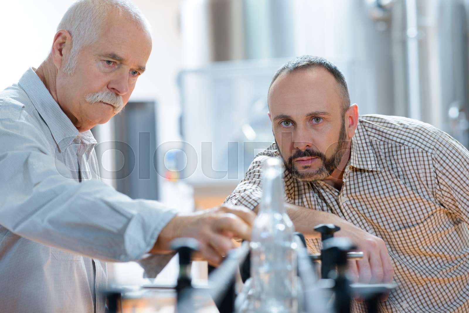 two men looking at the beaker with beer | Stock image | Colourbox