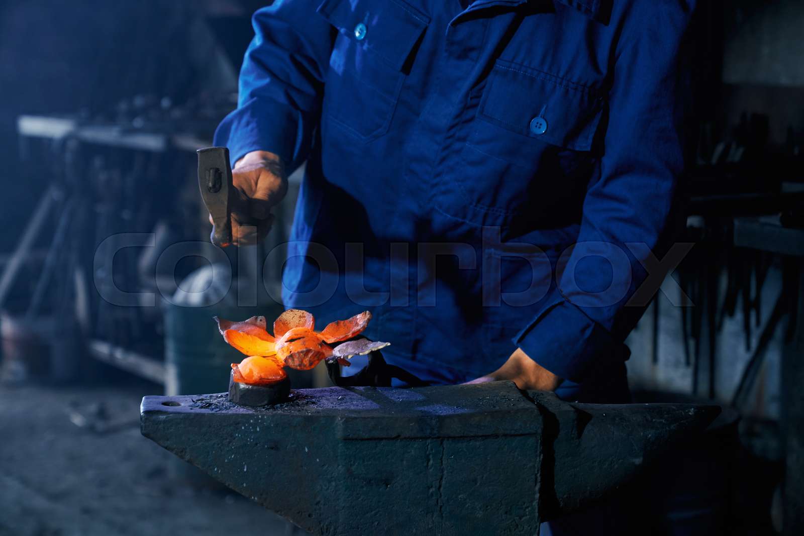 Blacksmith using heavy hammer for forging molten metal | Stock image ...
