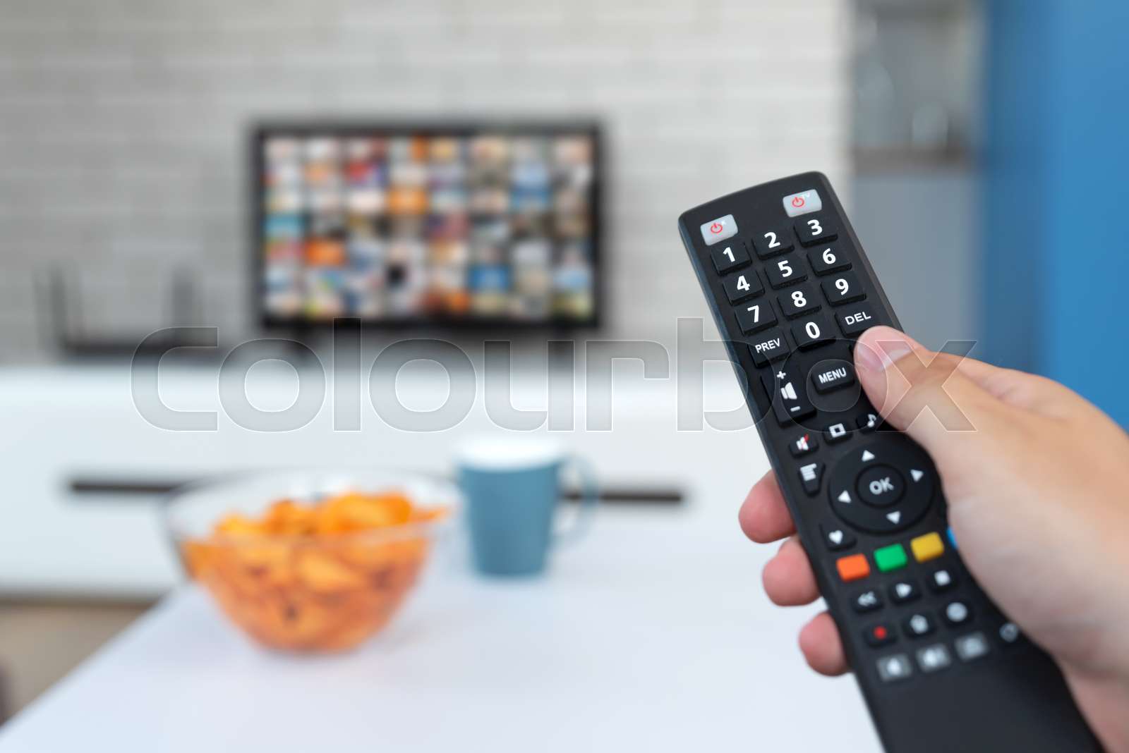Man watching TV, remote control in hand | Stock image | Colourbox