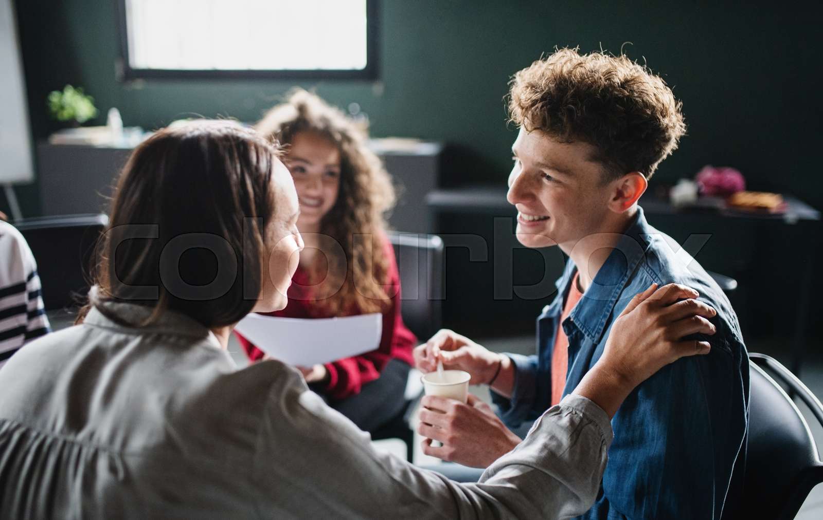Happy men and women sitting in circle during group therapy, talking ...
