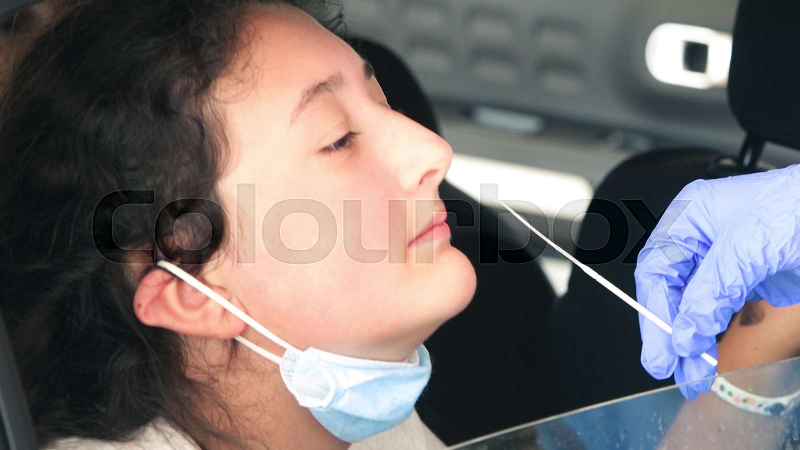 Doctor taking a swab for nasal test sample fom elementary age girl's ...