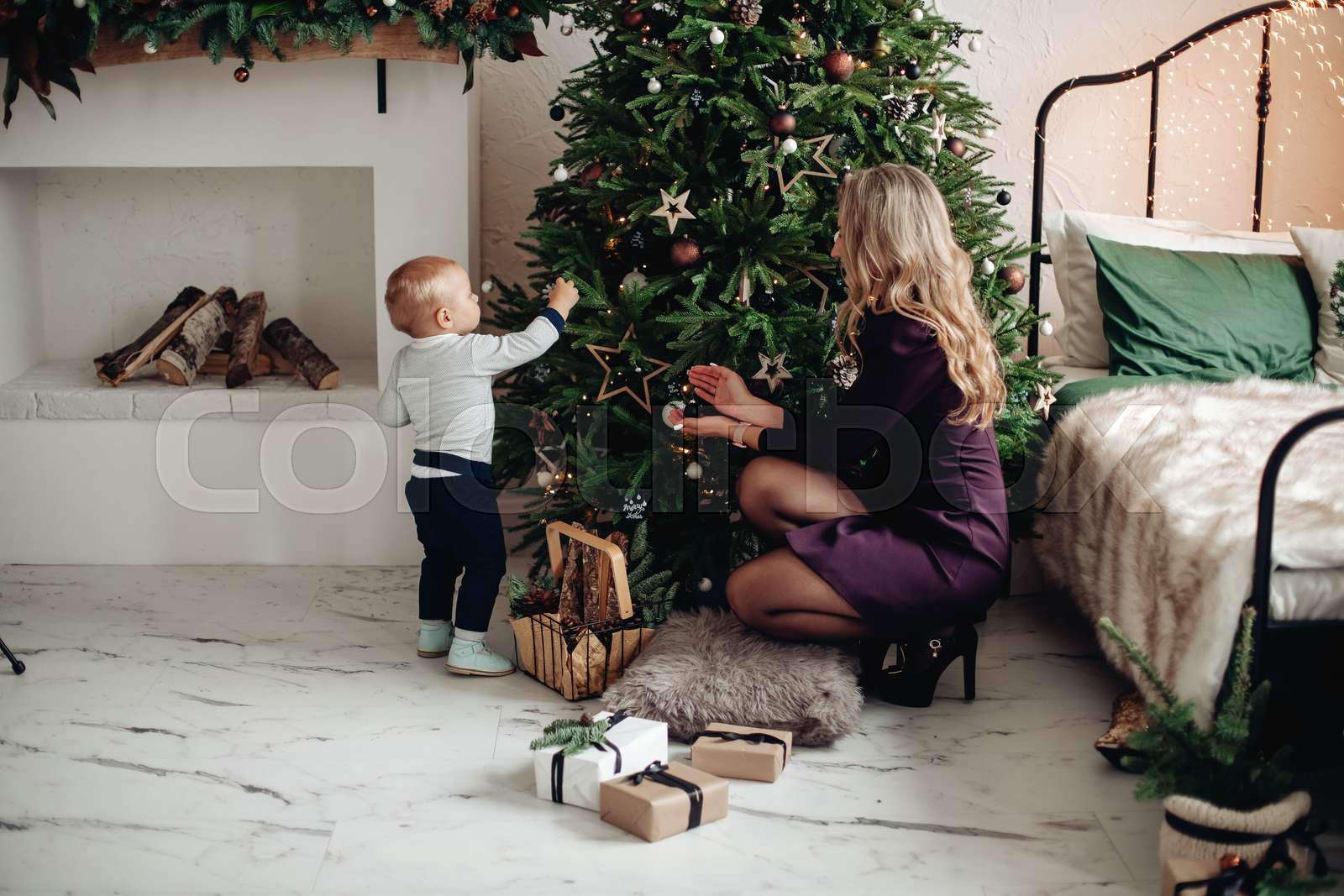Mom Decorates A Christmas Tree With Her Beloved Son At Home Stock