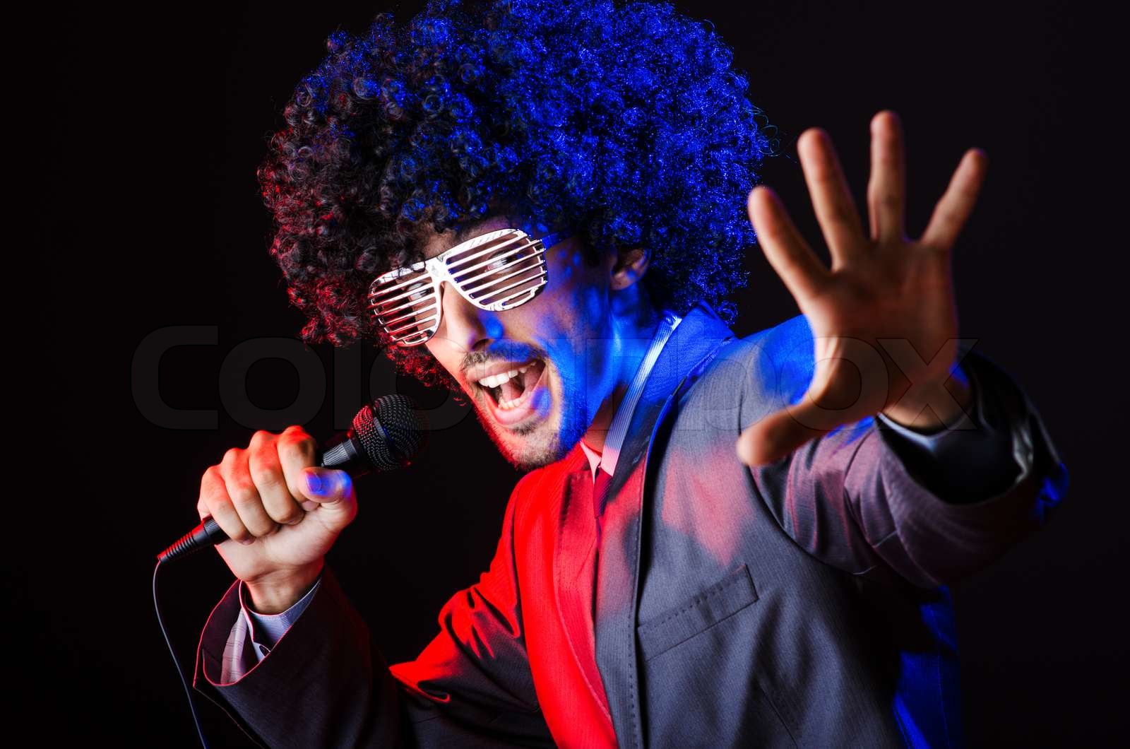 Young singer in afro wig singing at disco | Stock image | Colourbox