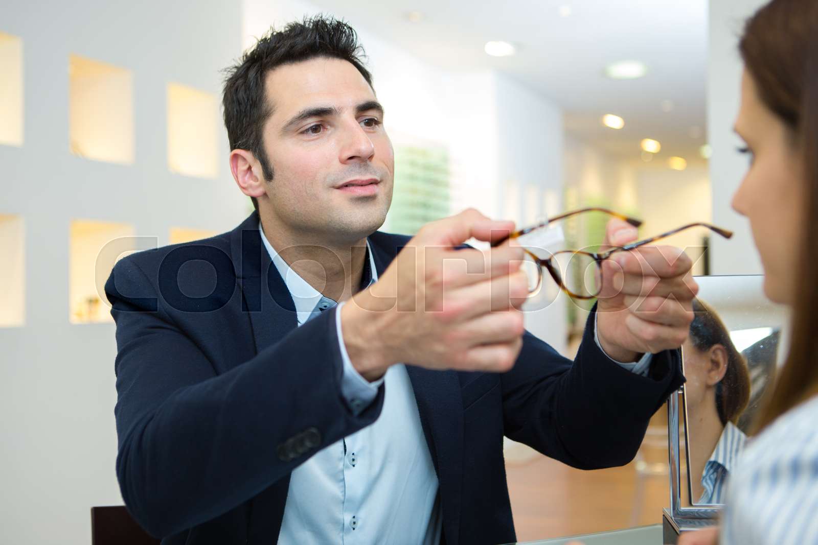 optician fitting eyeglasses on female customer | Stock image | Colourbox