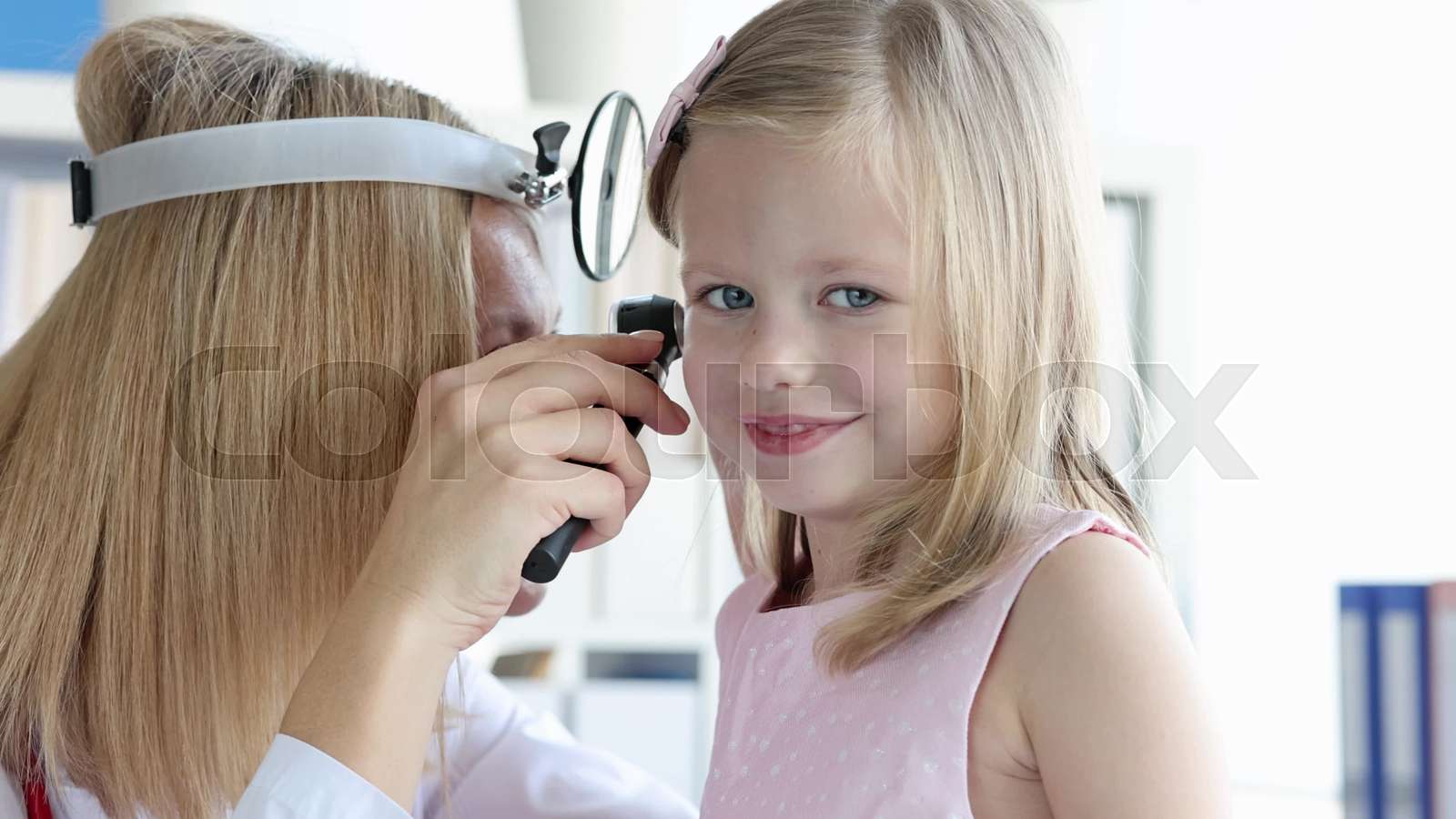 Ent with frontal reflector examining little girl ear with otoscope 4k ...