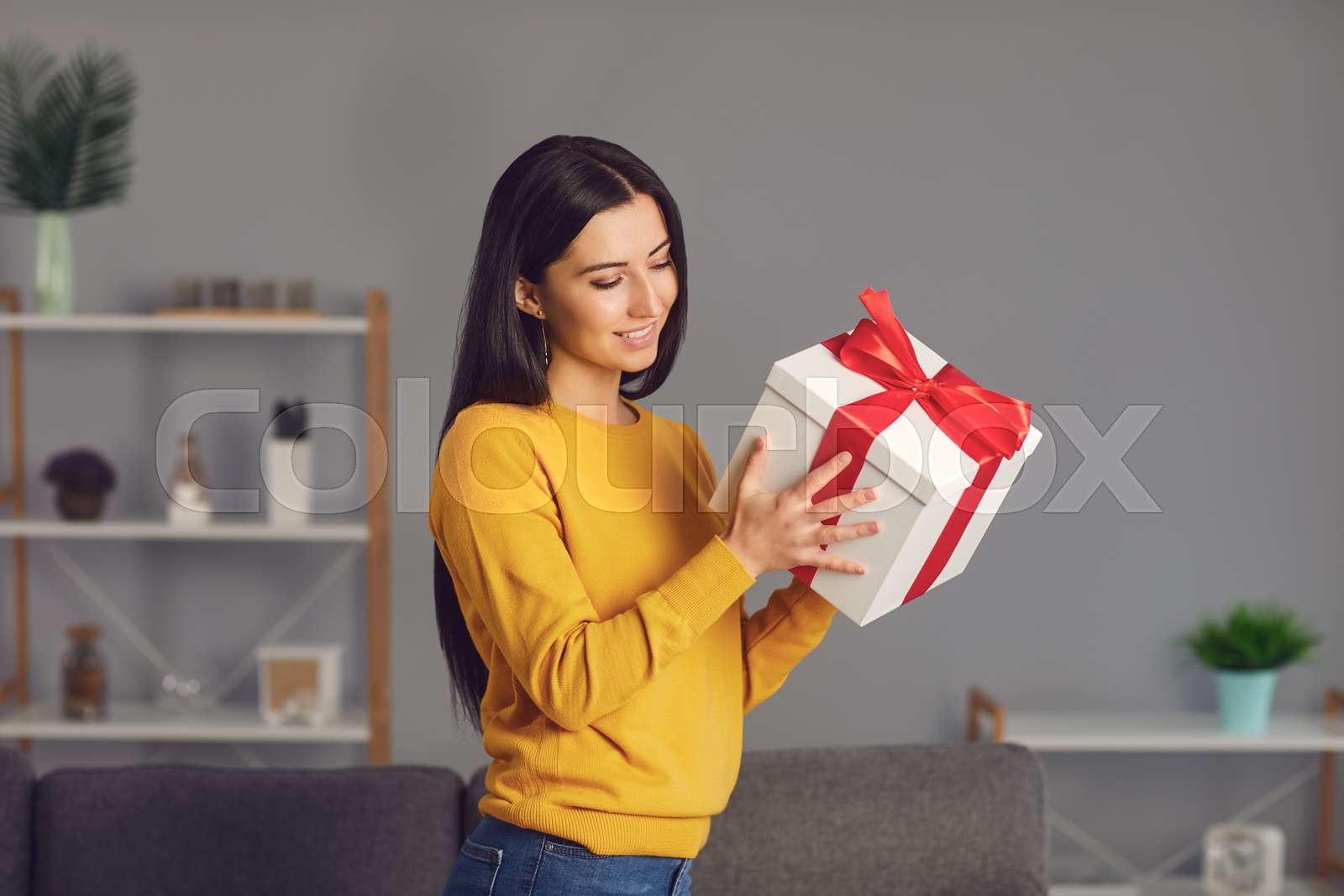 Charming woman holding present box with bow - Stock Image - Everypixel