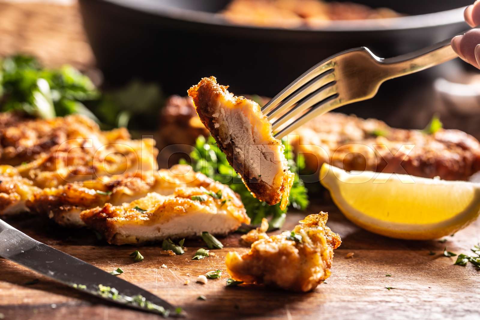 Viennese chicken steak on a fork. Traditional Austrian and German dish ...