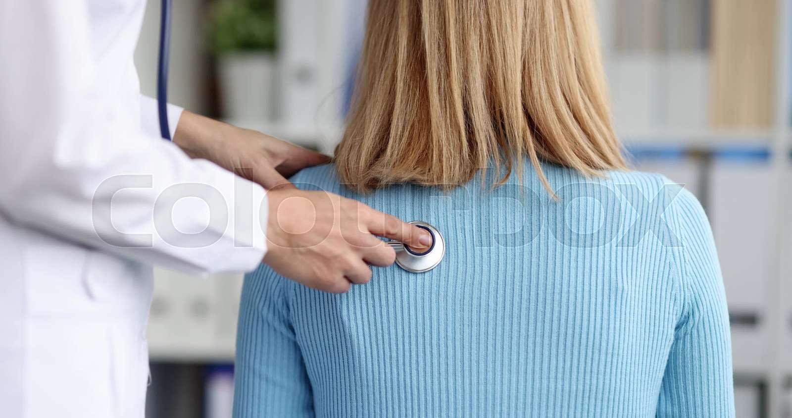 Doctor diagnoses patient breathing with stethoscope rear view | Stock ...