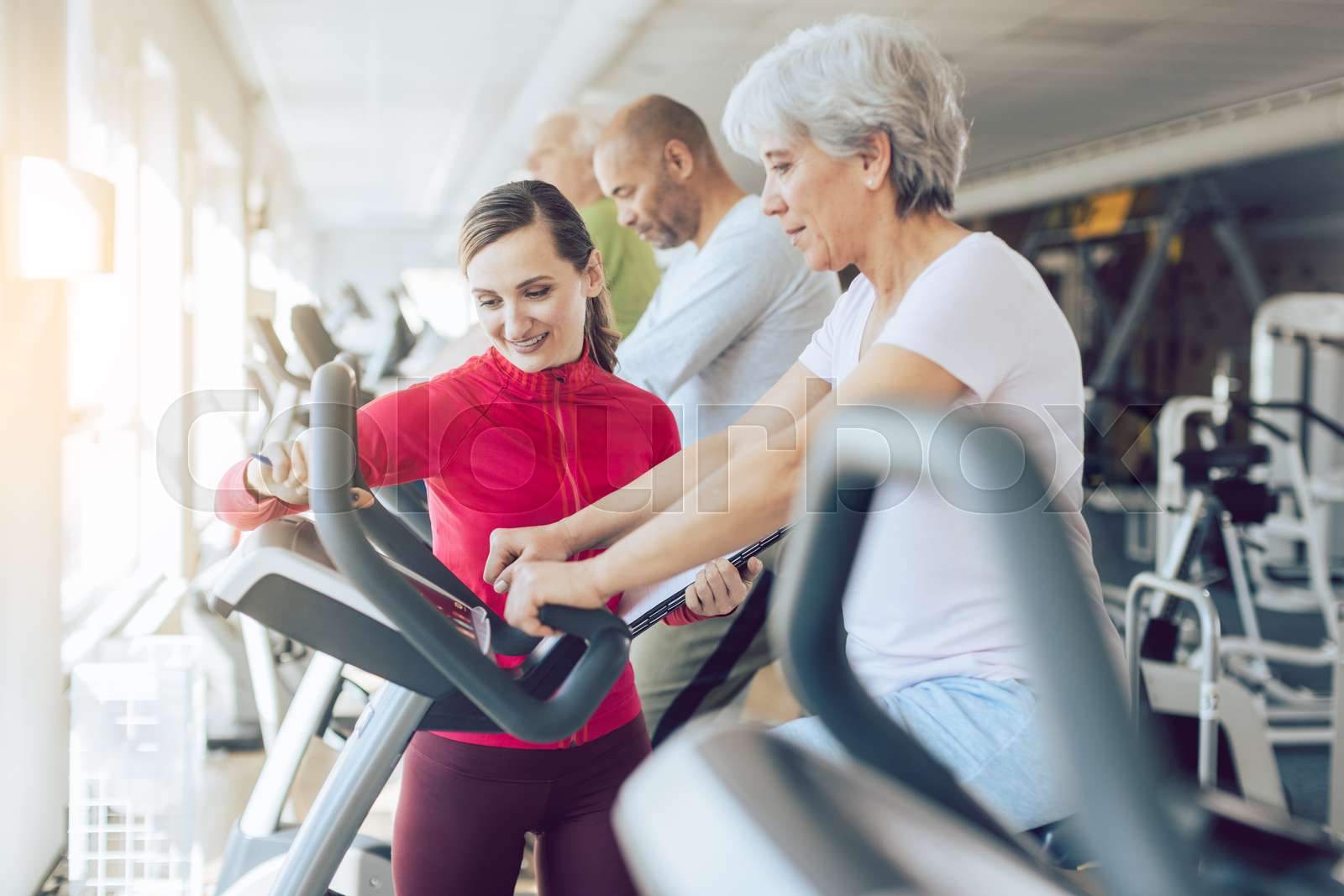 Fitness coach in gym helping senior people | Stock image | Colourbox