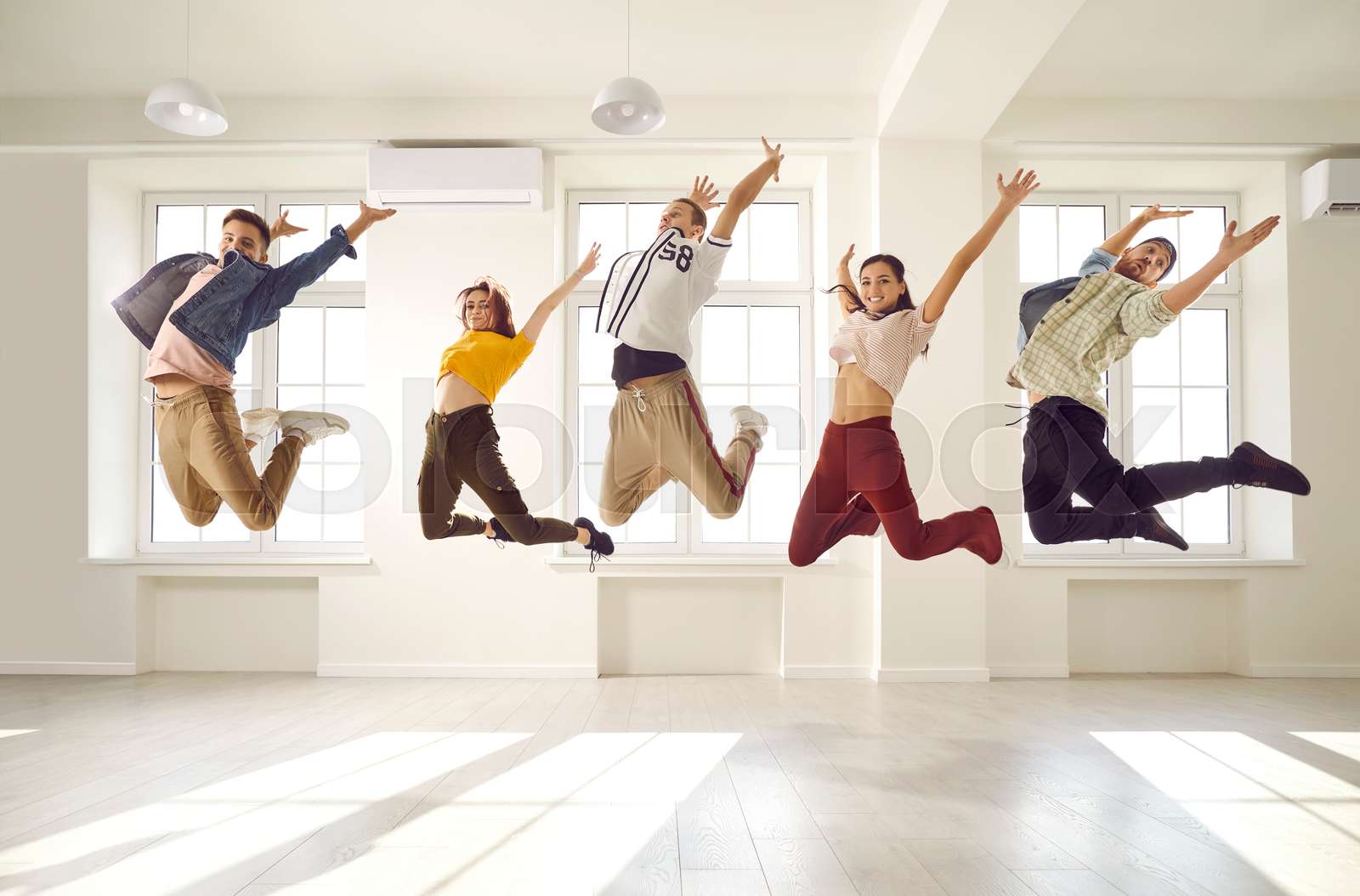 Group of happy contemporary dancers having fun and jumping high up in ...