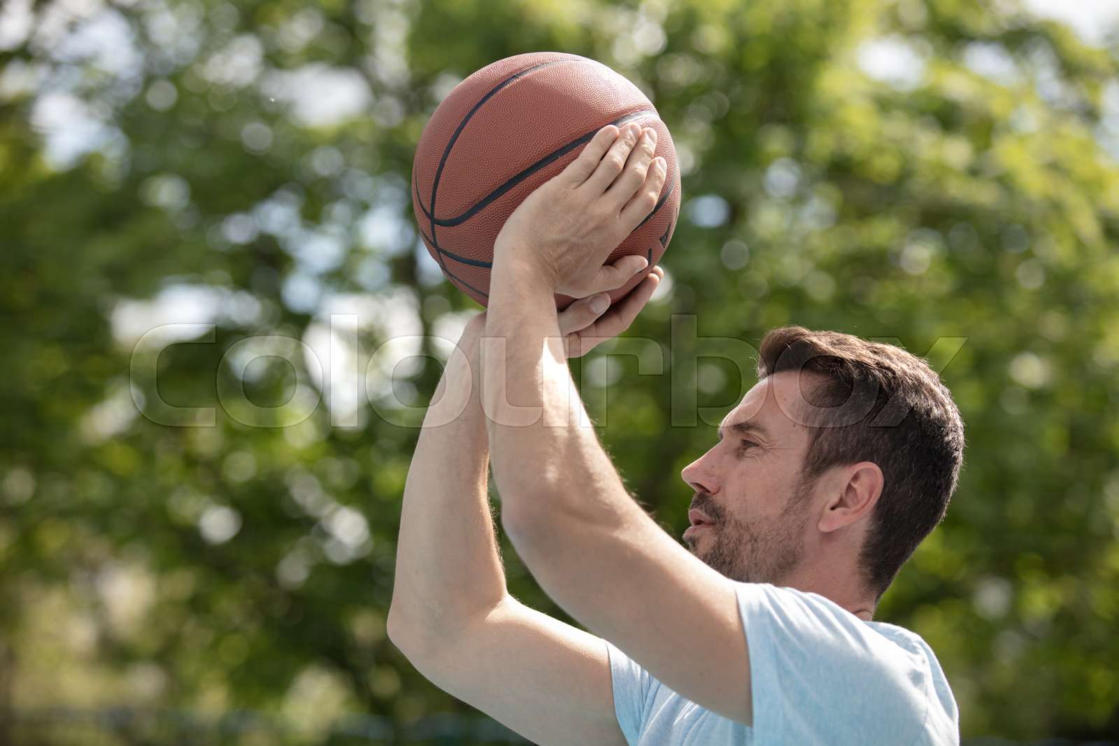 basketball player makes a throw on outdoor court | Stock image | Colourbox