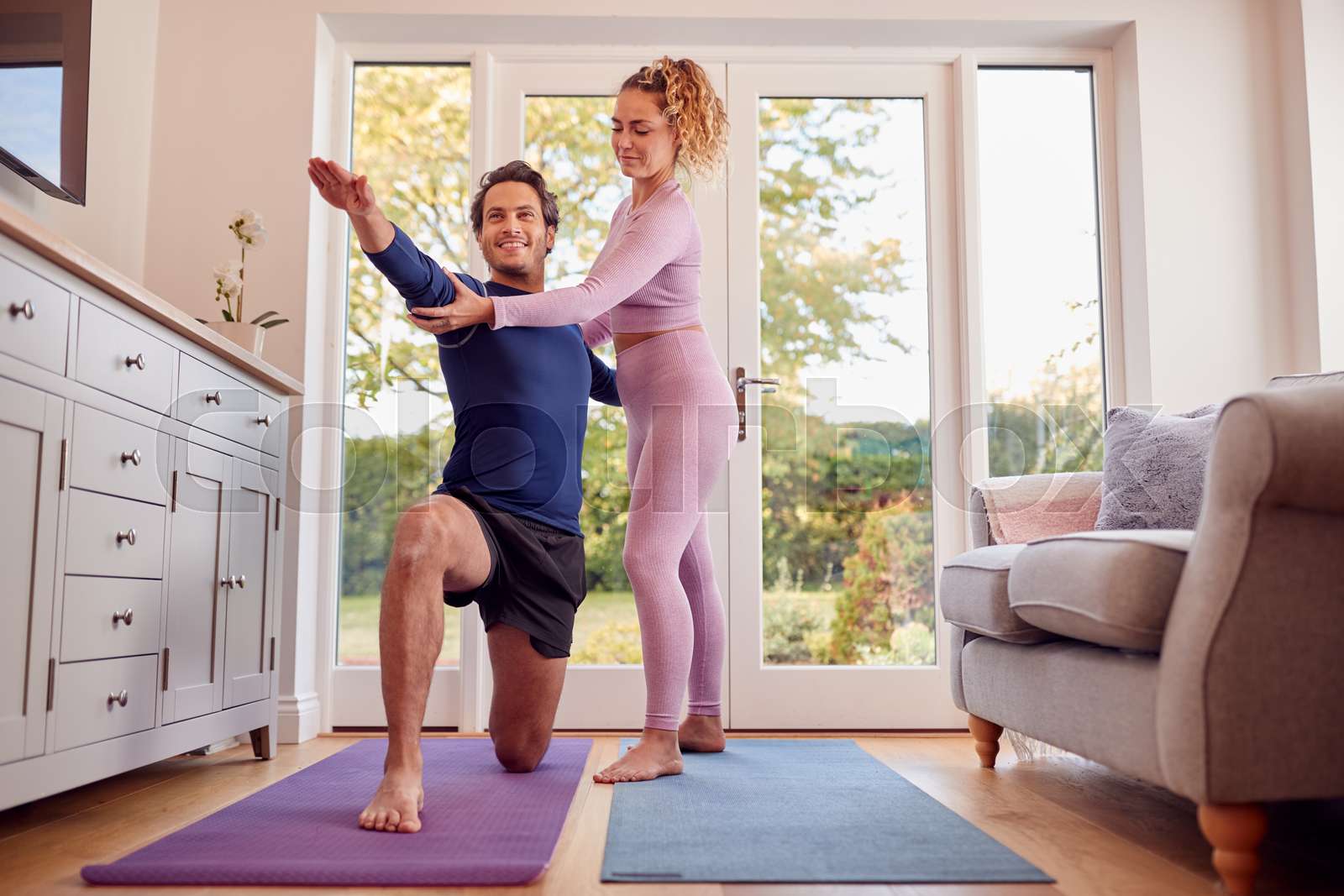 Female Yoga Teacher Helping Man With Home Yoga Class | Stock image ...