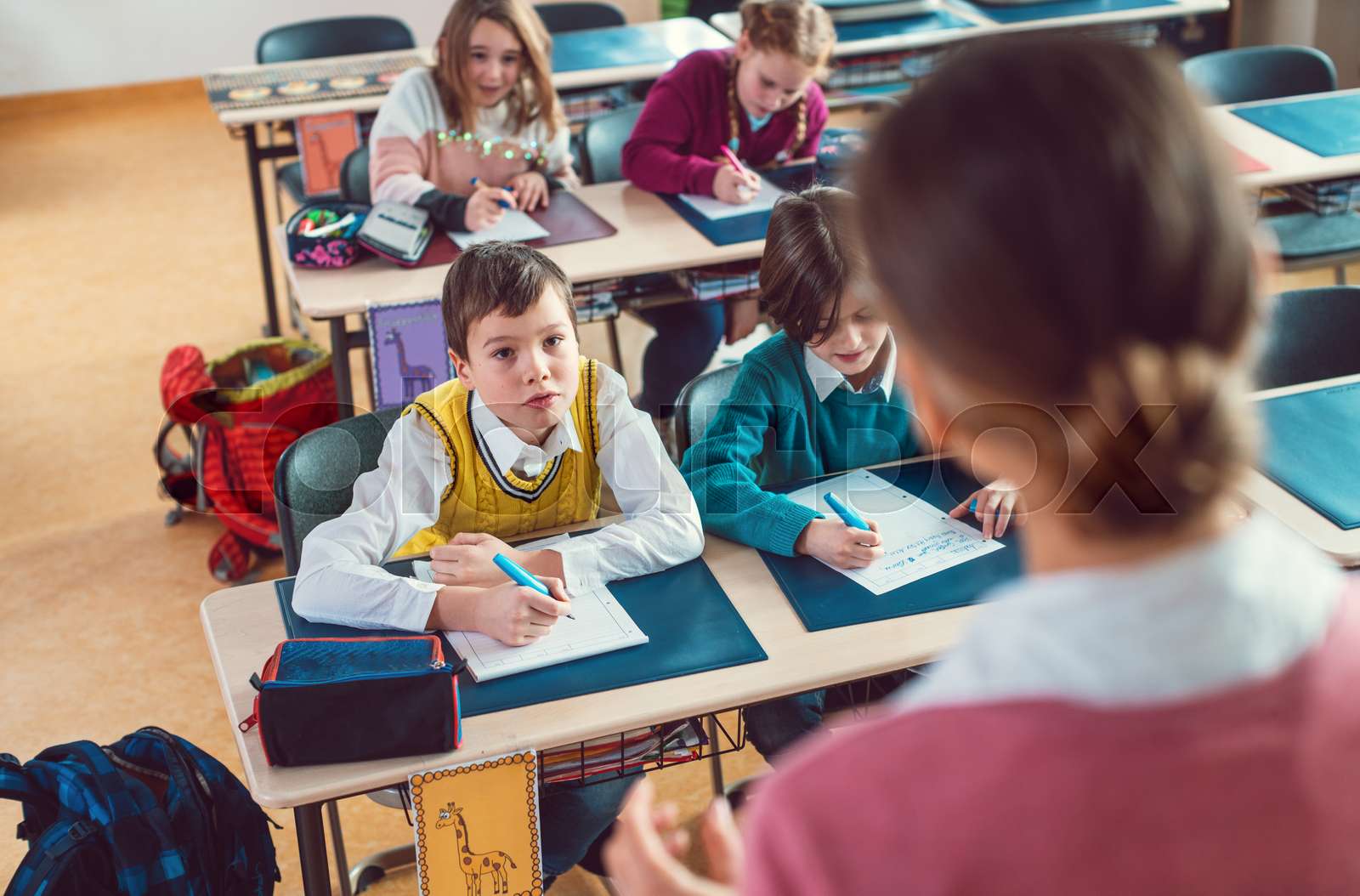 Pupils, boys and girls, in class listening to the school teacher ...