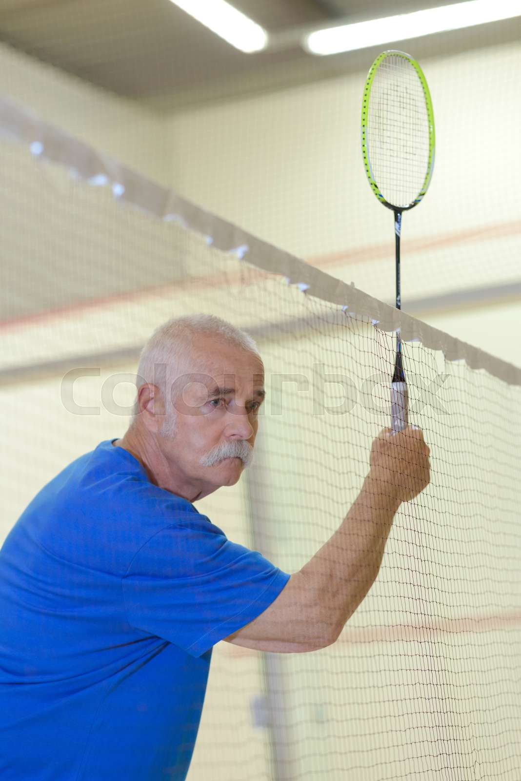 old man making a service while playing badminton | Stock image | Colourbox