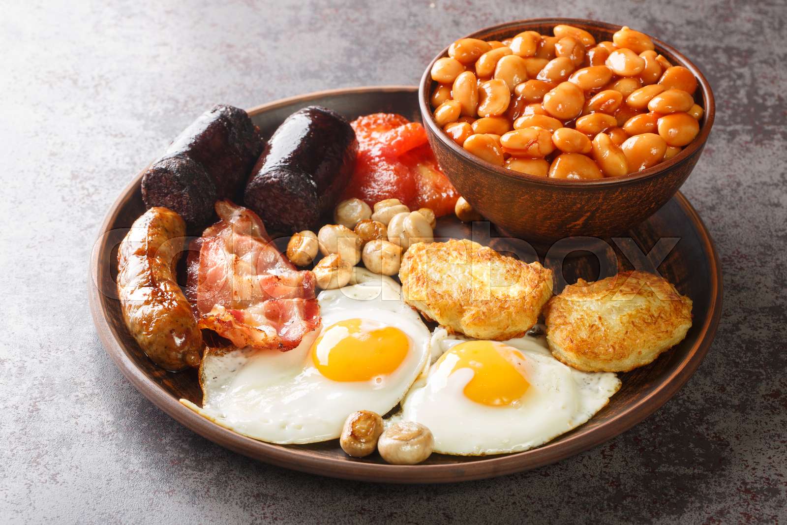 Full fry up English breakfast with fried eggs, sausages, bacon, black ...