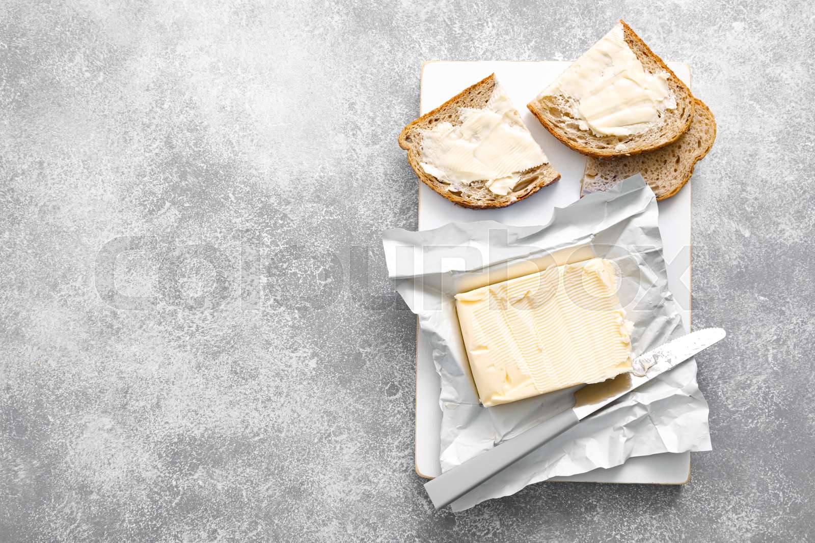 Block of butter with butter knife in a open pack. Buttering bread ...