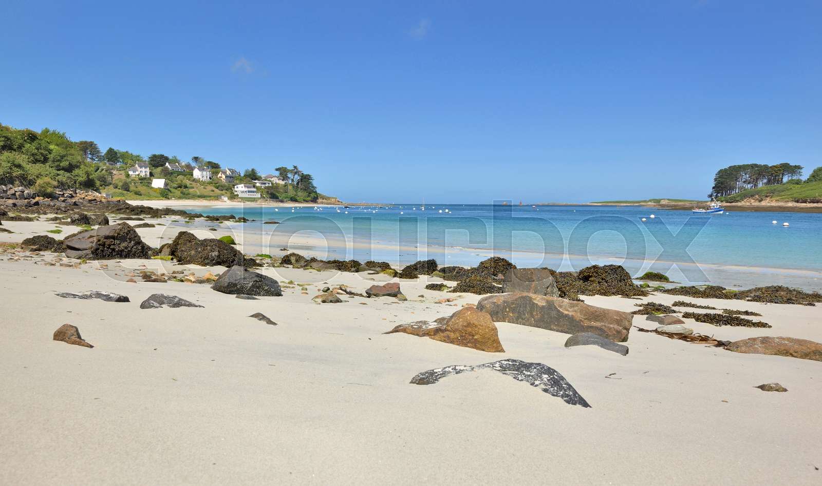 view of a beach with fine white sand and rocks in front of blue water ...