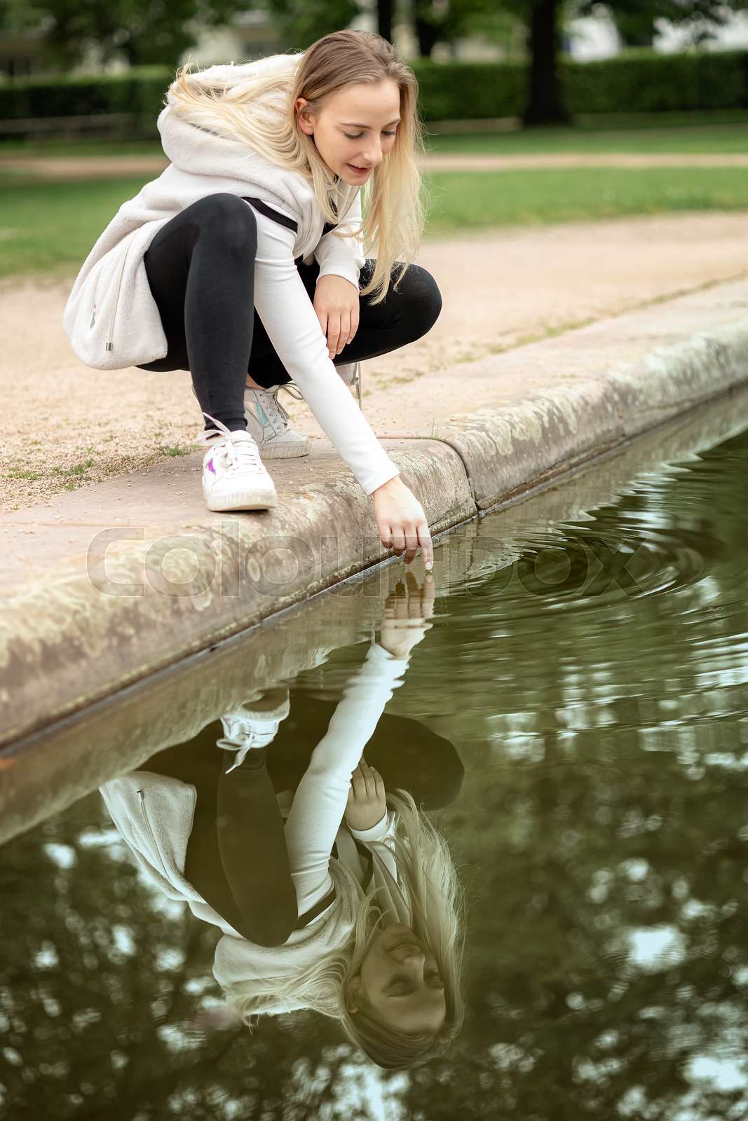 Young girl near a pond with reflection in the water | Stock image ...