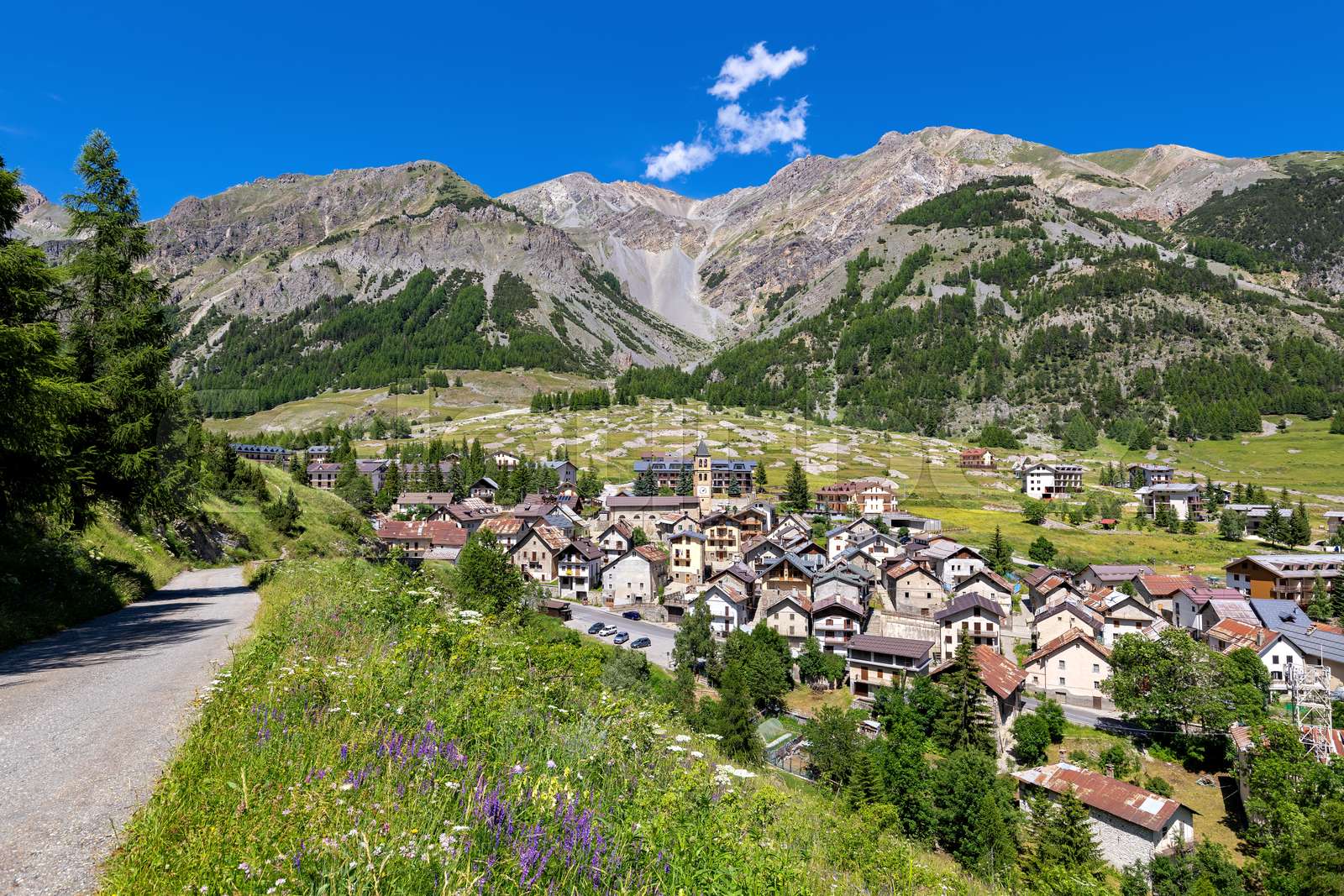 Small alpine town on the green valley among mountains in Northern Italy ...