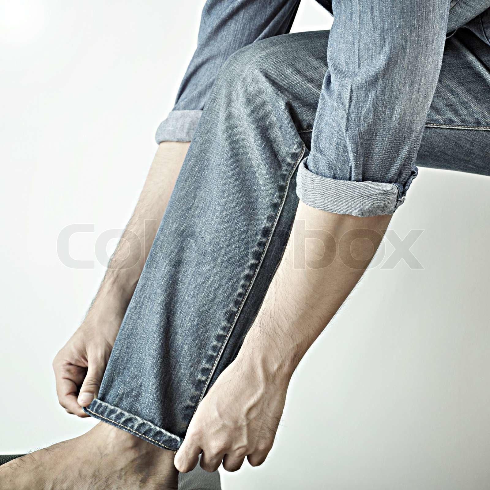 Man wearing jeans folding up pant leg | Stock image | Colourbox
