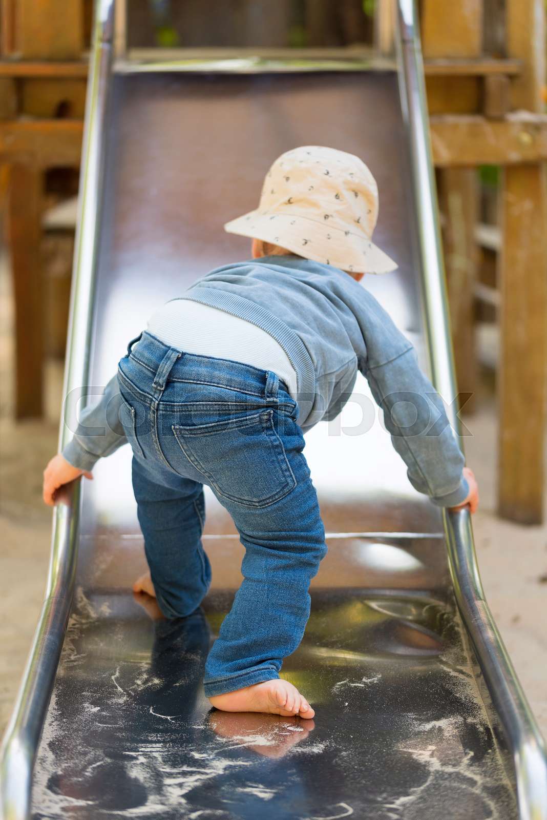 toddler climbing up slide on playground | Stock image | Colourbox