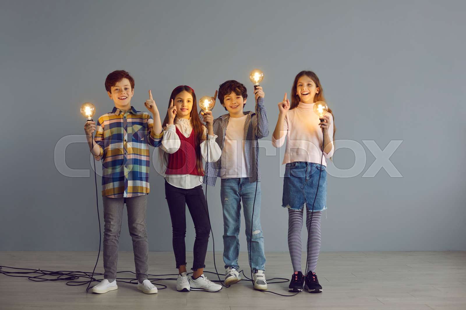 Group of creative clever kids holding shining light bulbs and pointing ...