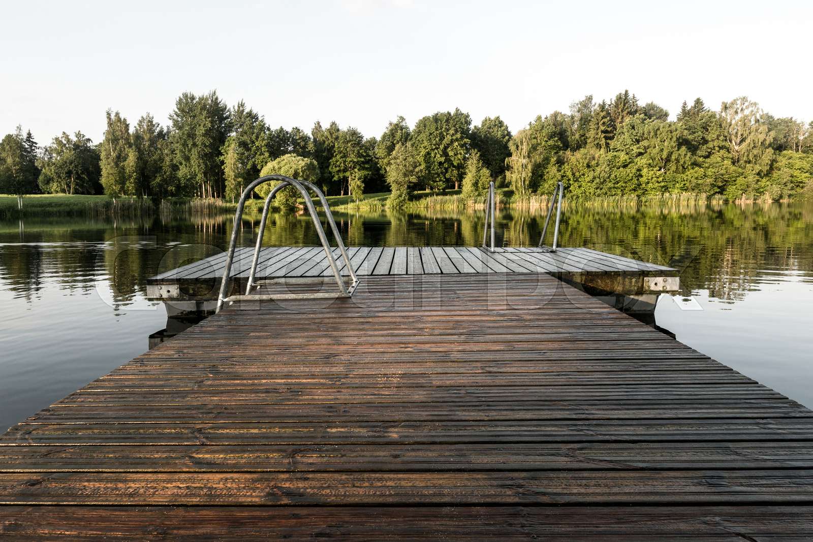 Wet wooden pier in smooth water of lake | Stock image | Colourbox