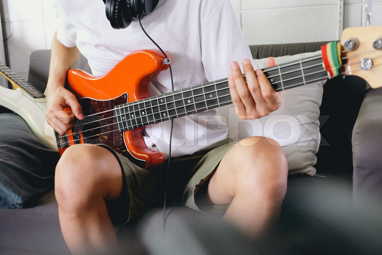 Musician playing bass guitar on sofa | Stock image | Colourbox