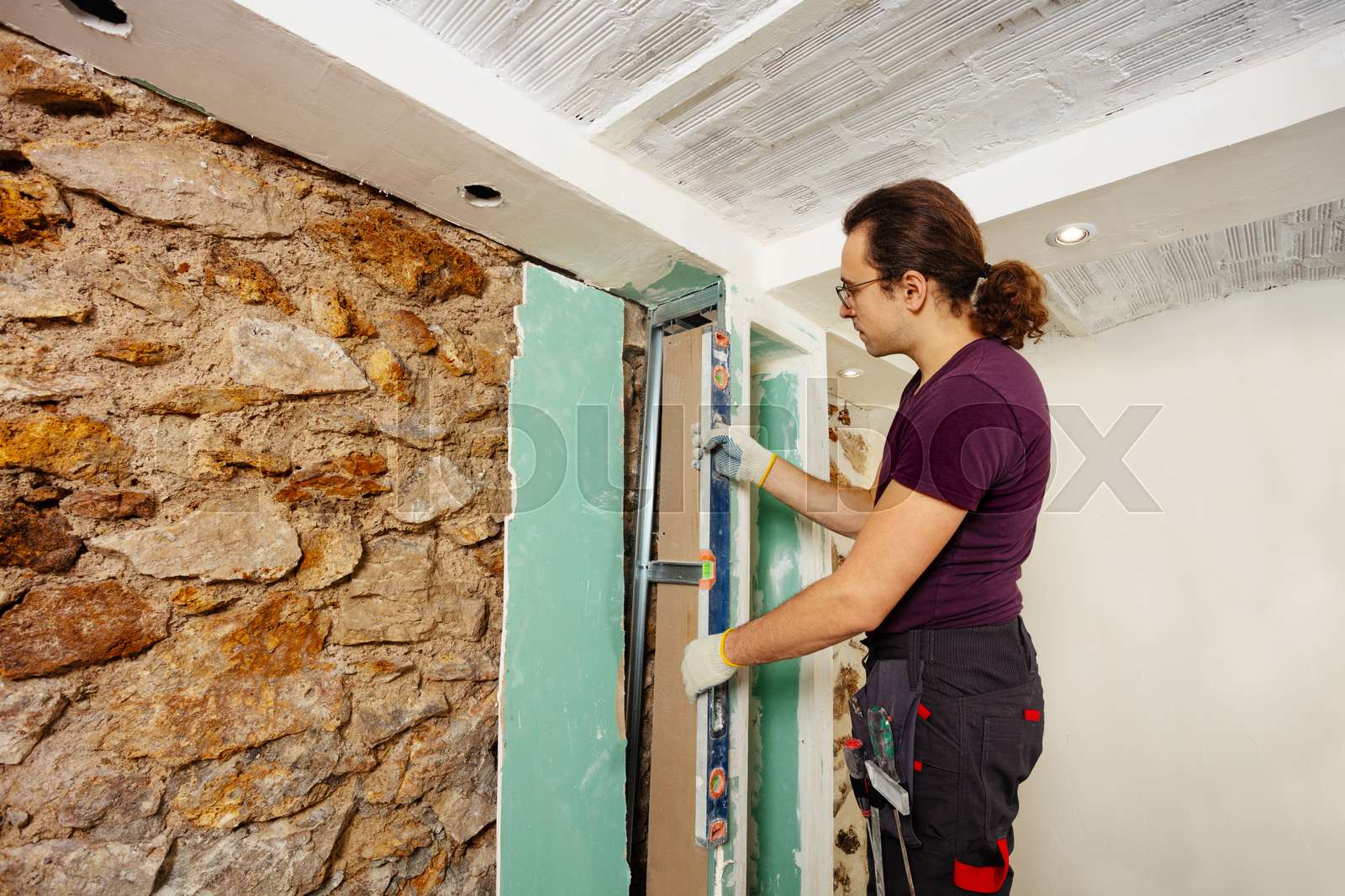 Man with a level at his home assembling drywall | Stock image | Colourbox