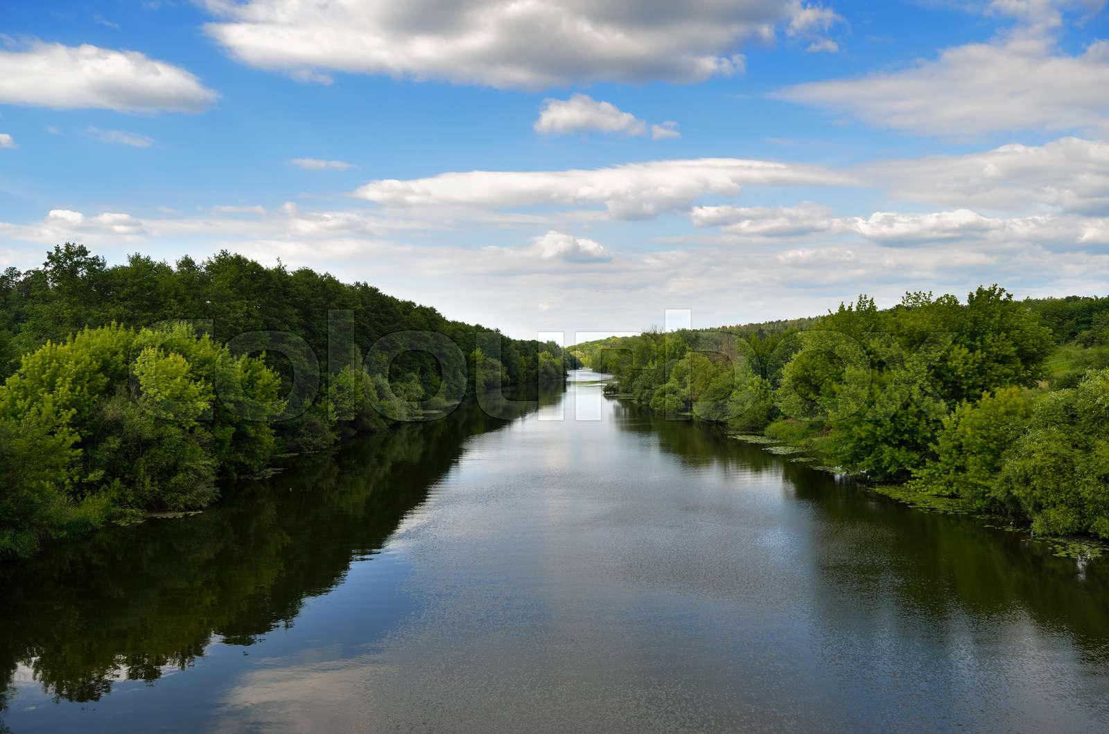 River in a forest area against a blue sky | Stock image | Colourbox