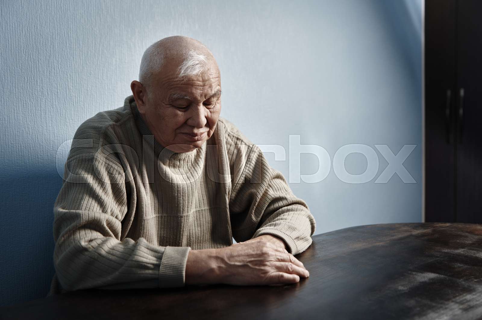 Pensive and thoughtful senior man sitting at the table | Stock image ...
