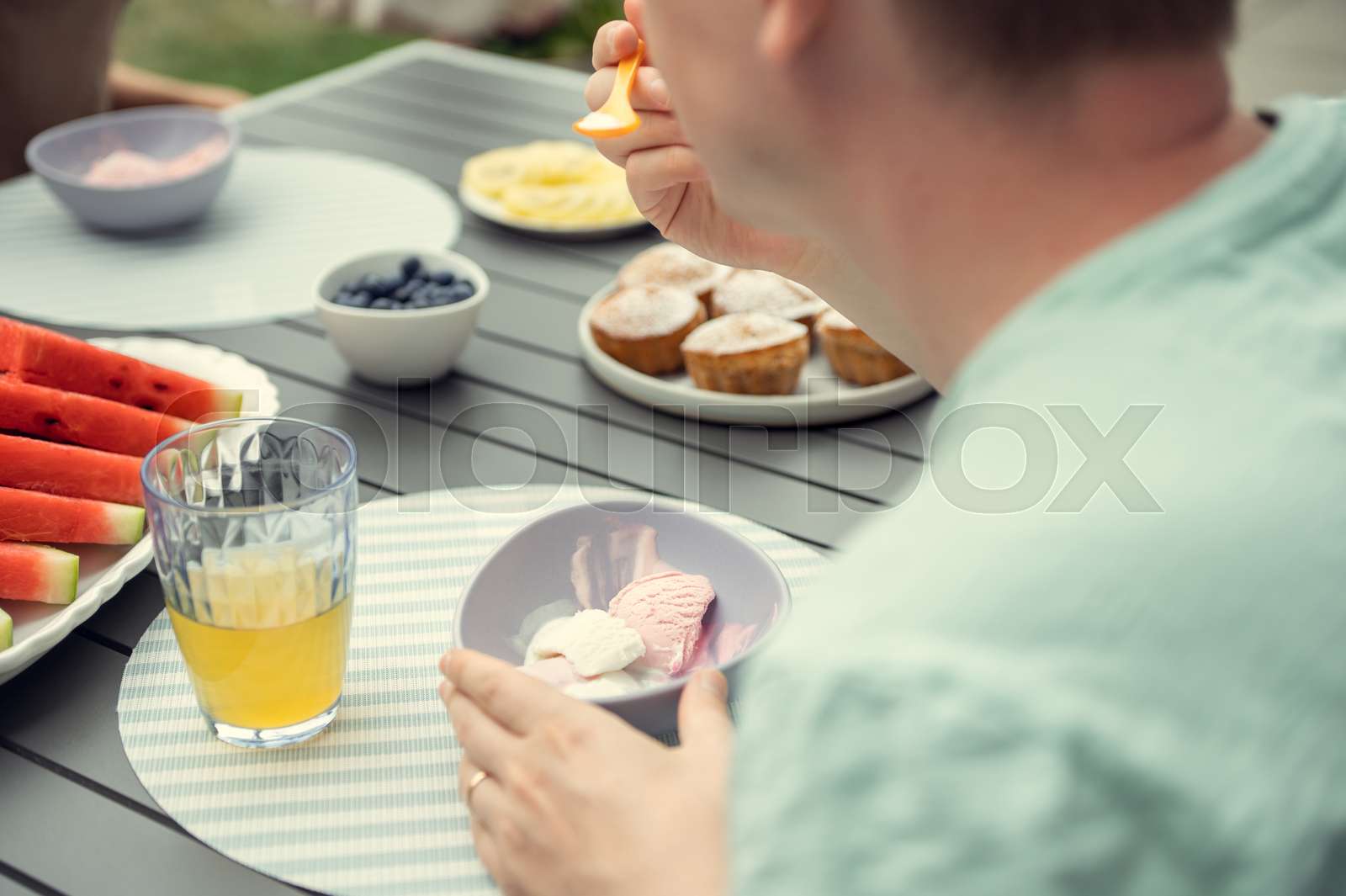 Young man eating ice-cream and sweets in outdoor cafe | Stock image ...