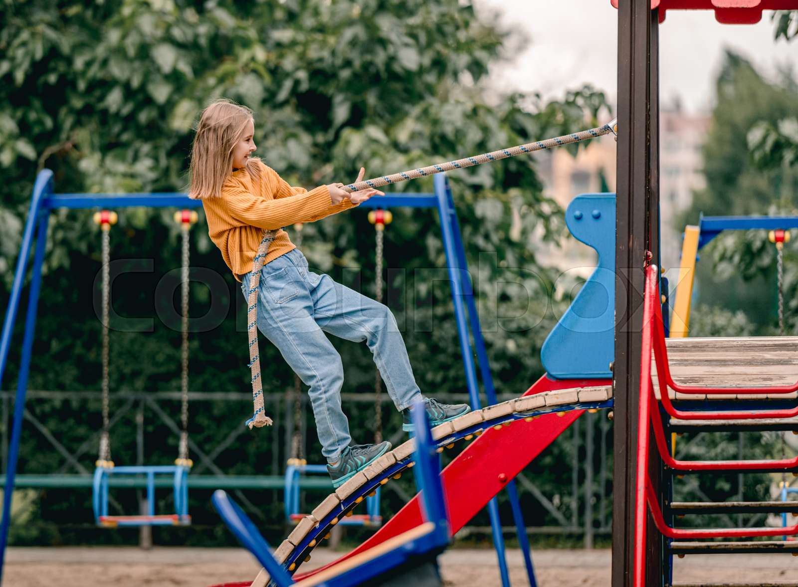 Little girl climbing rope on playground | Stock image | Colourbox