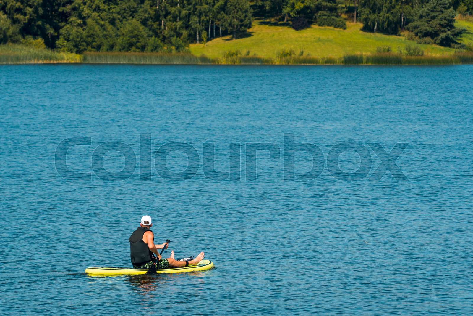 Side view foto of a man swimming and relaxing on the sup board | Stock ...
