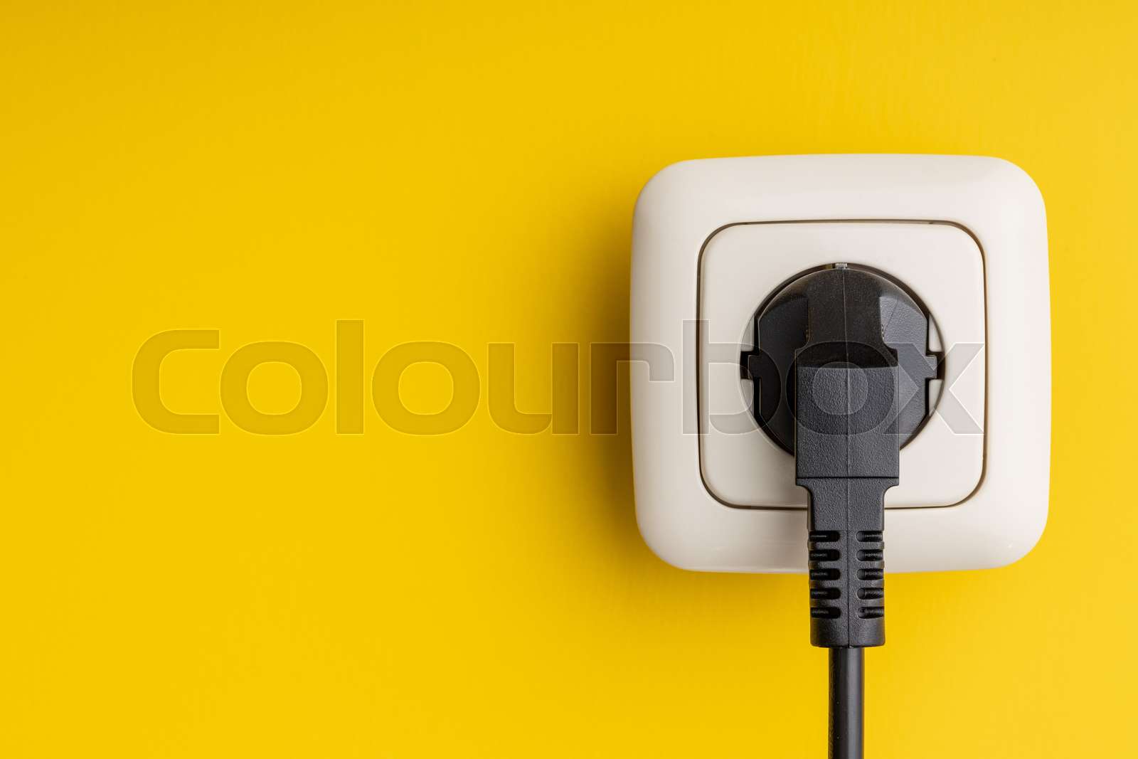 Electric plug and wall socket on yellow wall. | Stock image | Colourbox