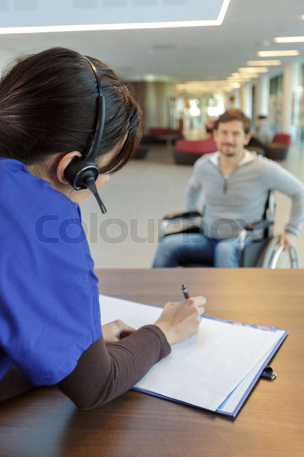 patient in wheelchair approaching receptionist | Stock image | Colourbox