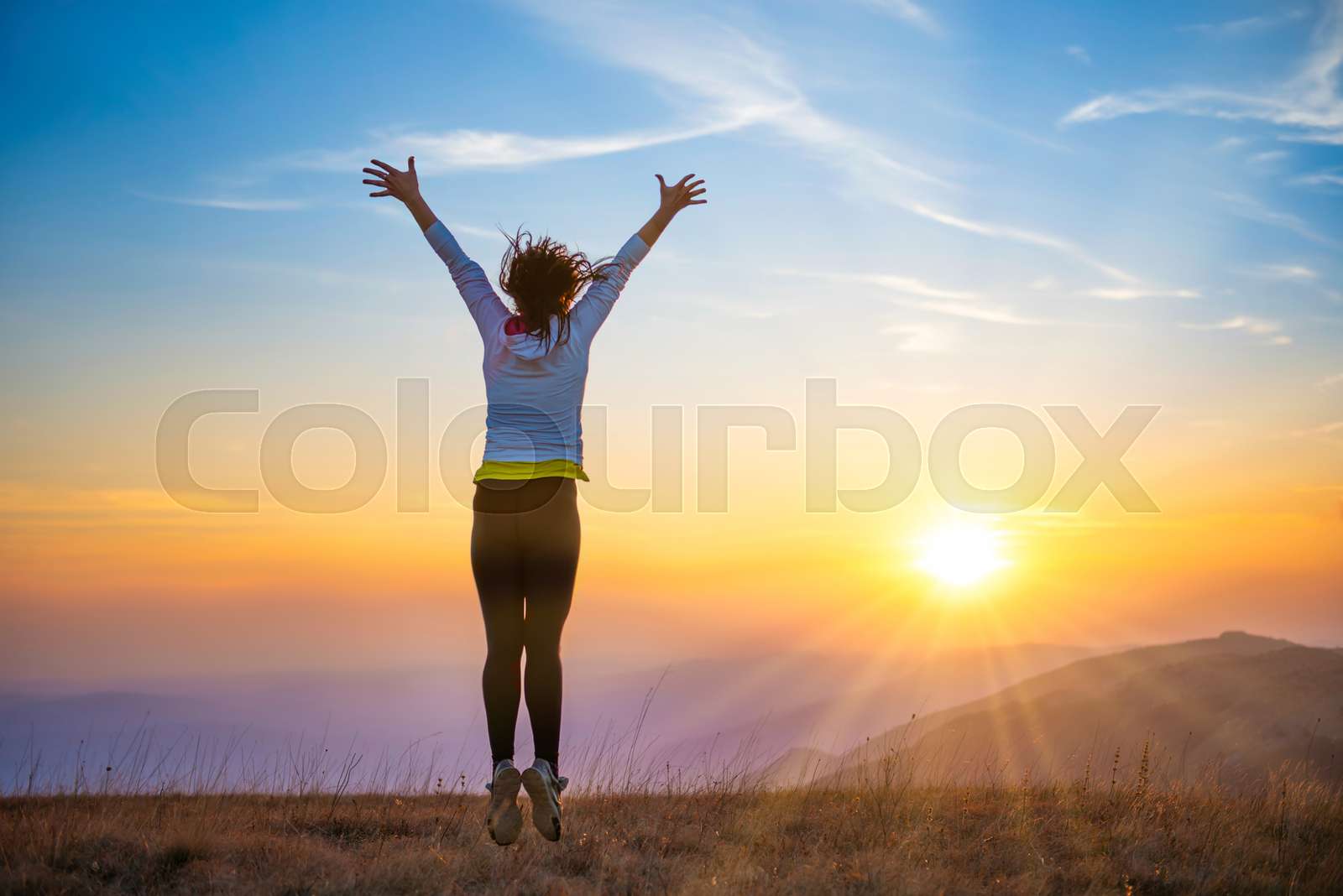 Young woman jumping at sunset mountains | Stock image | Colourbox